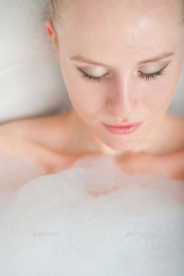 caucasian woman enjoying bathtub. Naturally beautiful female relaxing in bath with foam in ...